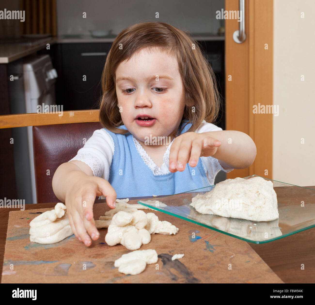 Cute little girl learning to make the dough figurines in the room Stock ...