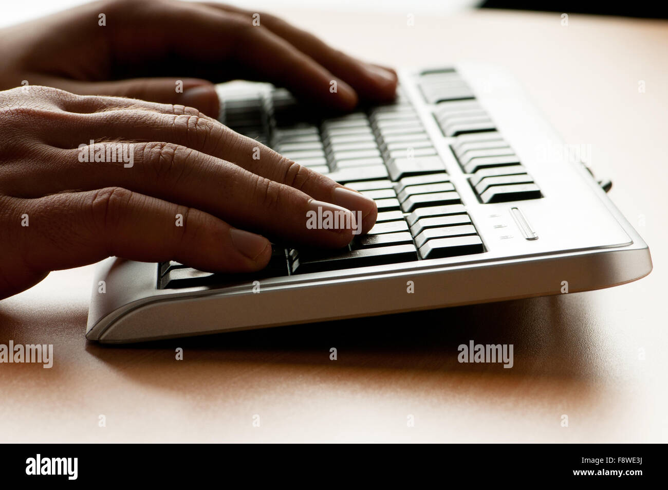 Two hands working on the silver keyboard Stock Photo - Alamy