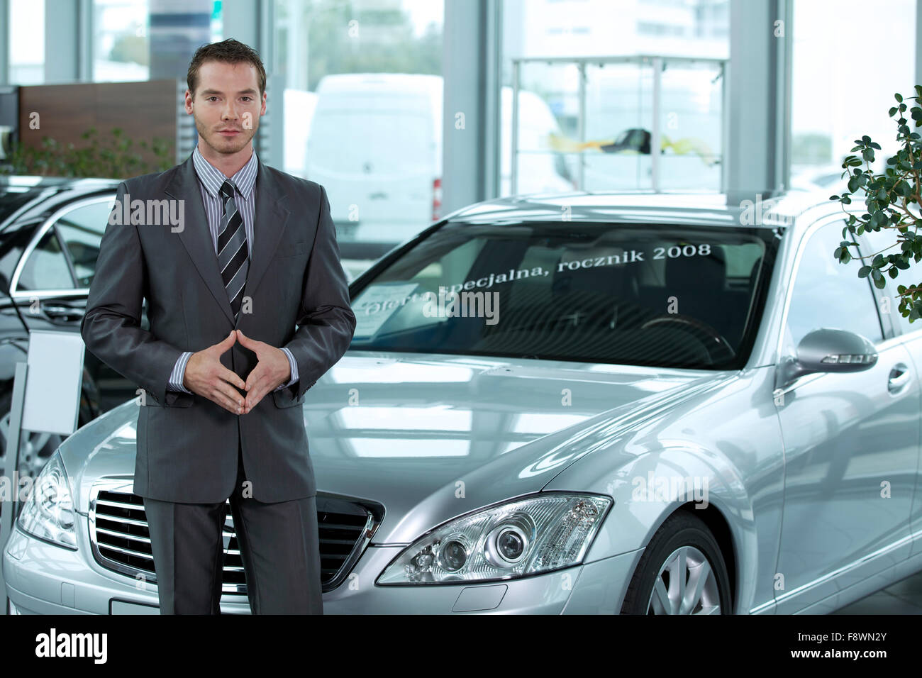 Portrait of car salesperson standing in car showroom Stock Photo - Alamy