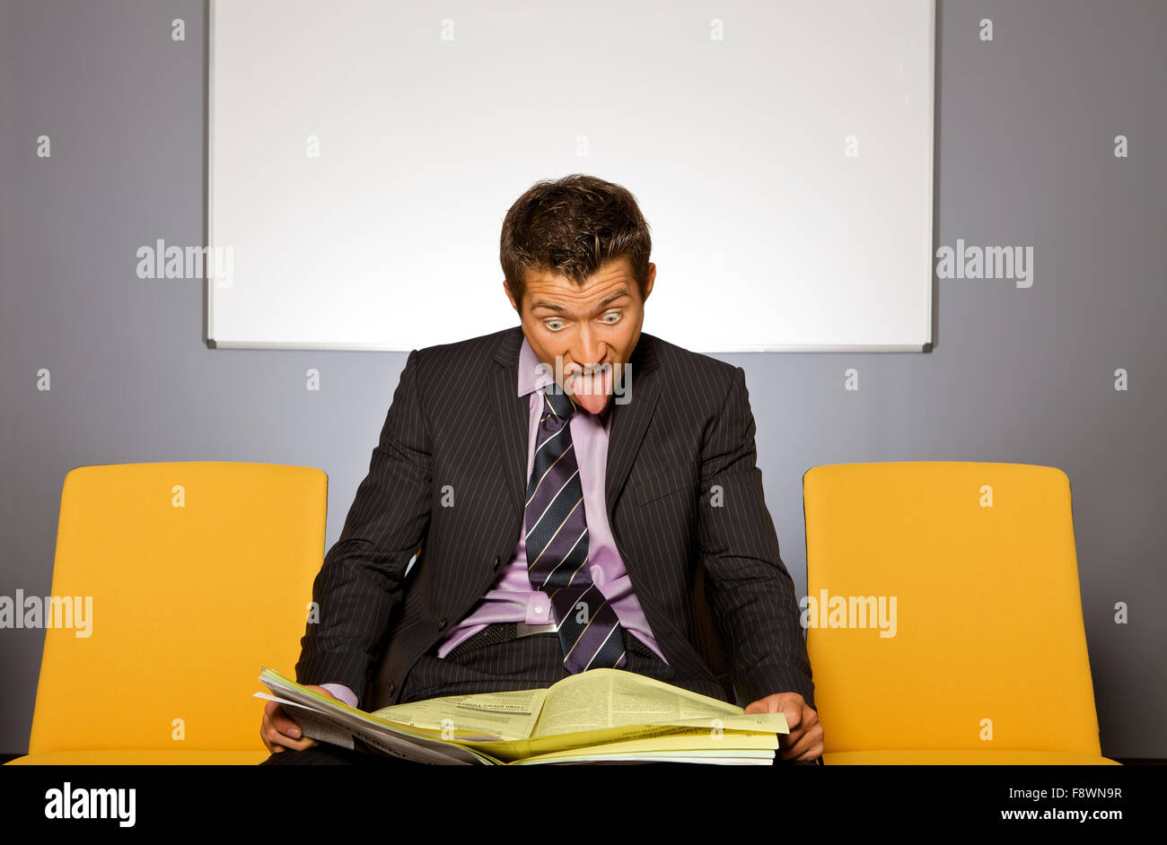 Businessman shocked while reading newspaper Stock Photo - Alamy