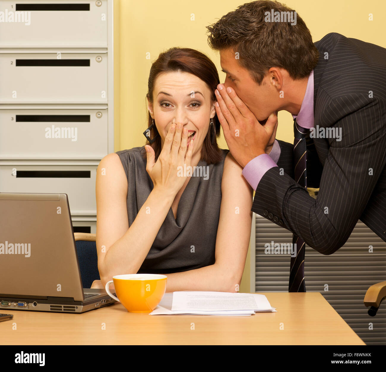 Businessman whispering in businesswoman's ear at office Stock Photo - Alamy