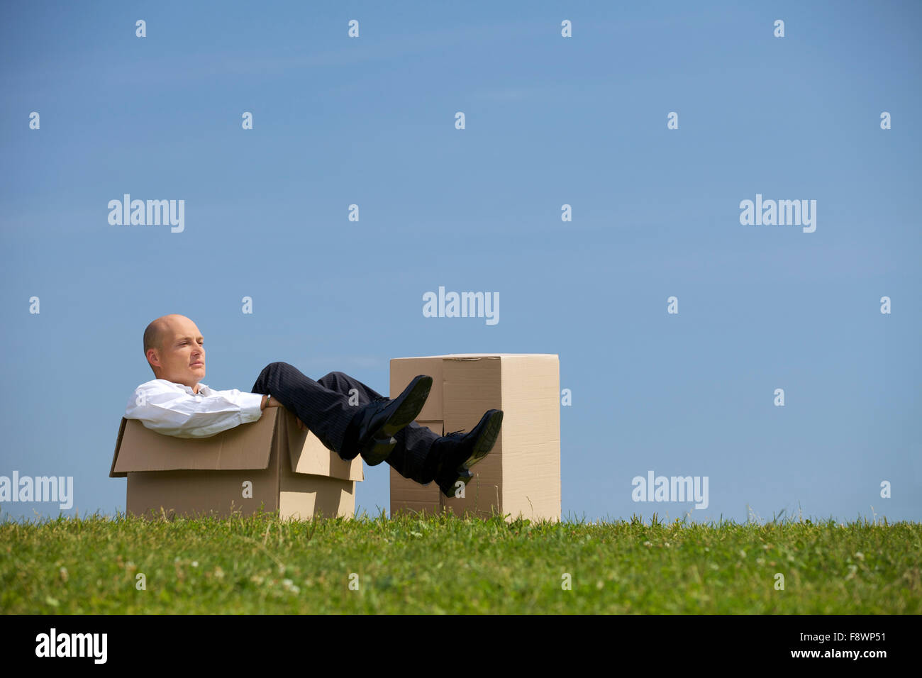 Young man relaxing in cardboard box at park Stock Photo - Alamy