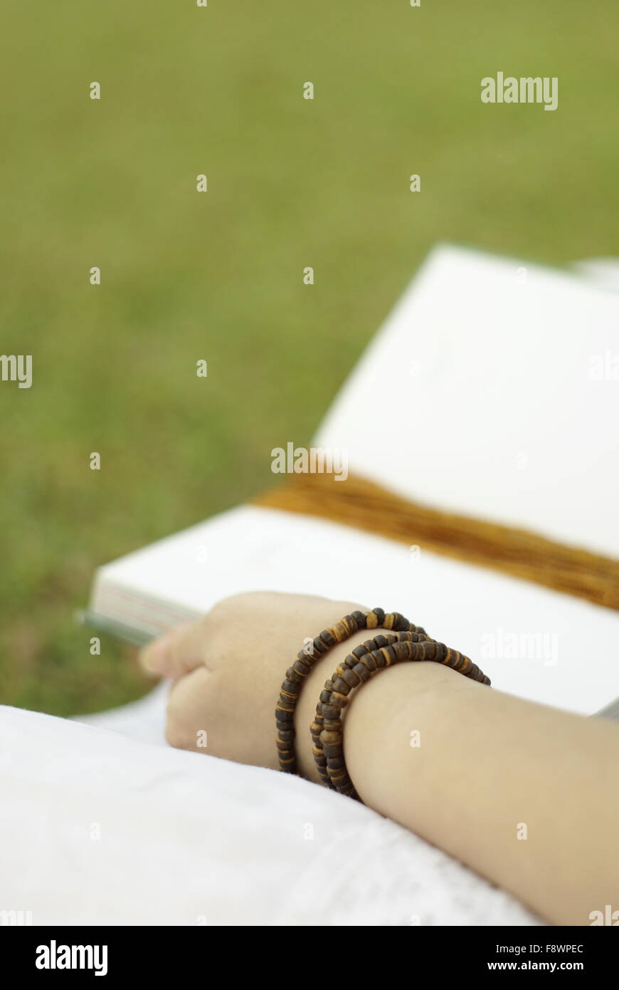Reading book outdoors with green grass background Stock Photo - Alamy