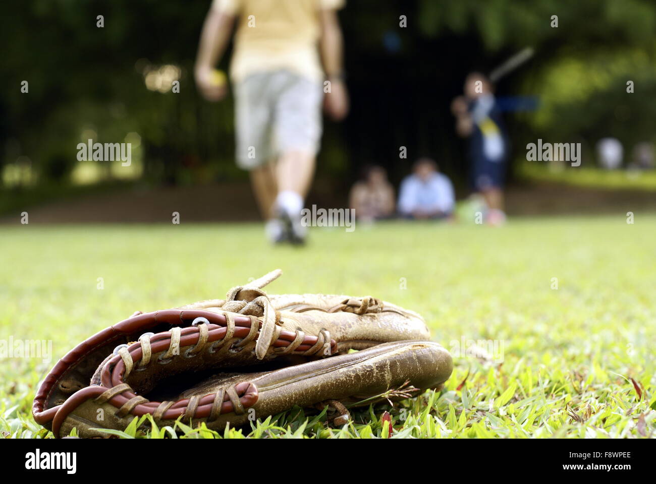 People playing softball outdoors with focus on catcher's glove on grass ...