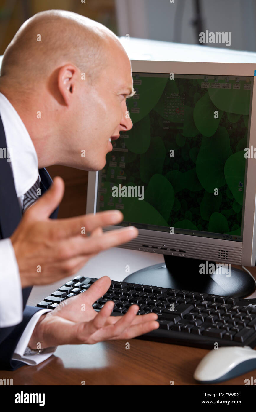 Businessman frowning in front of computer monitor Stock Photo - Alamy