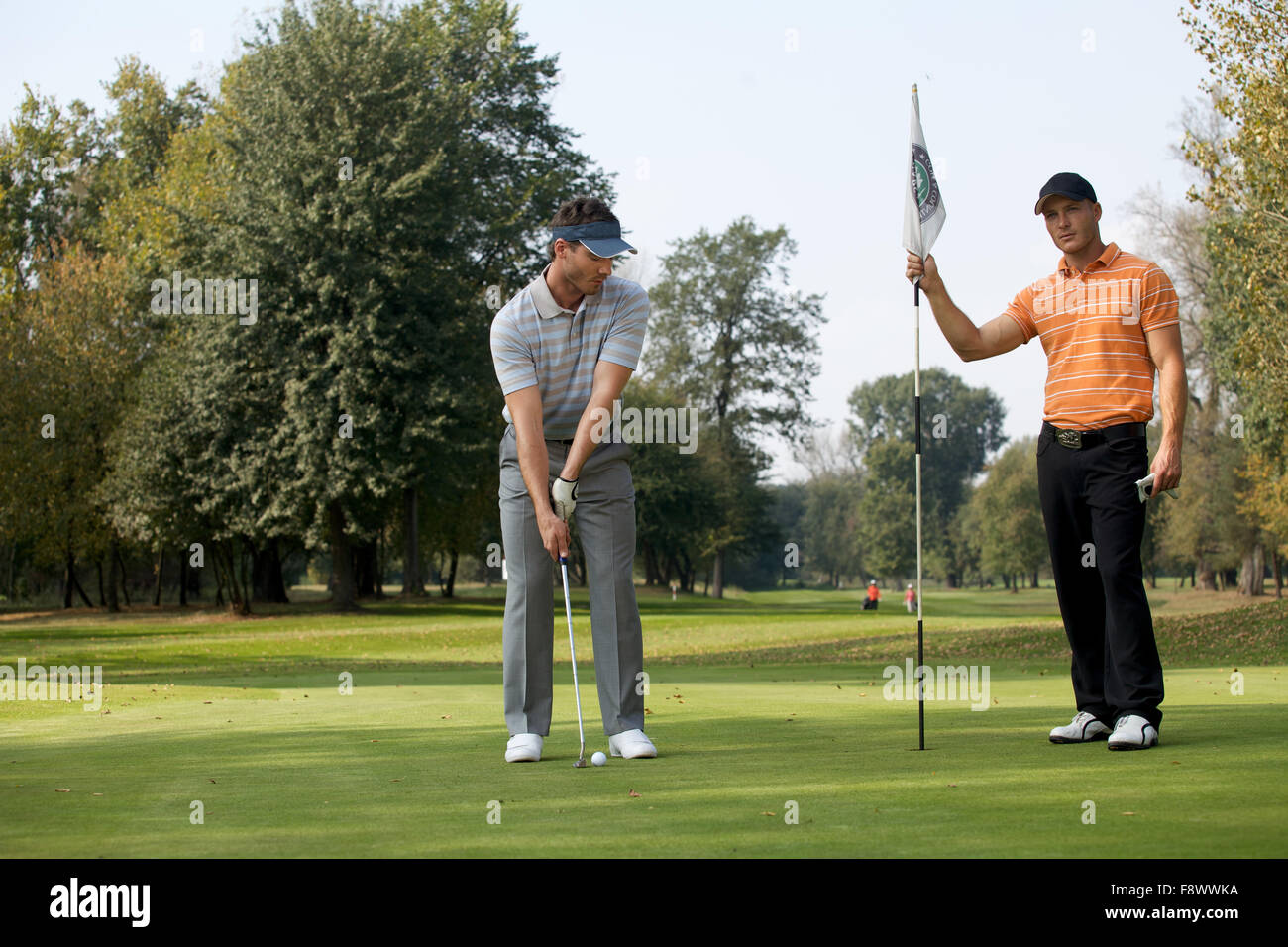 Portrait of young men standing with golf sticks on golf course Stock ...