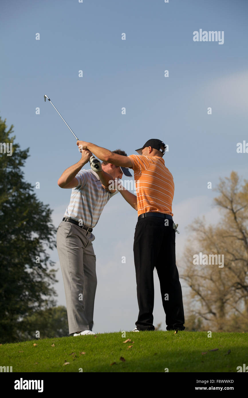 Golf professional helping young man with his swing Stock Photo - Alamy