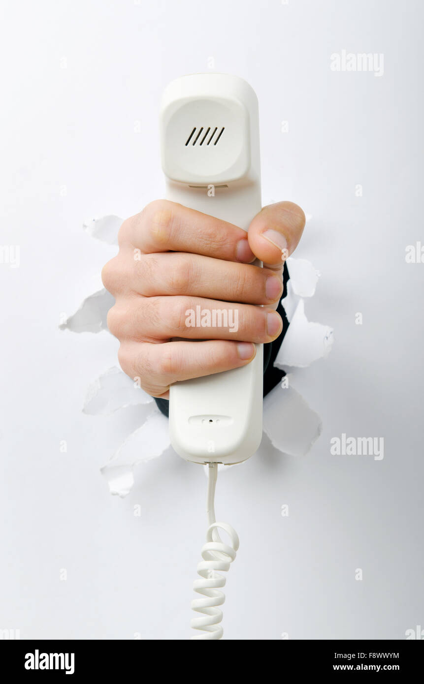 Hand holding phone through hole in paper Stock Photo - Alamy