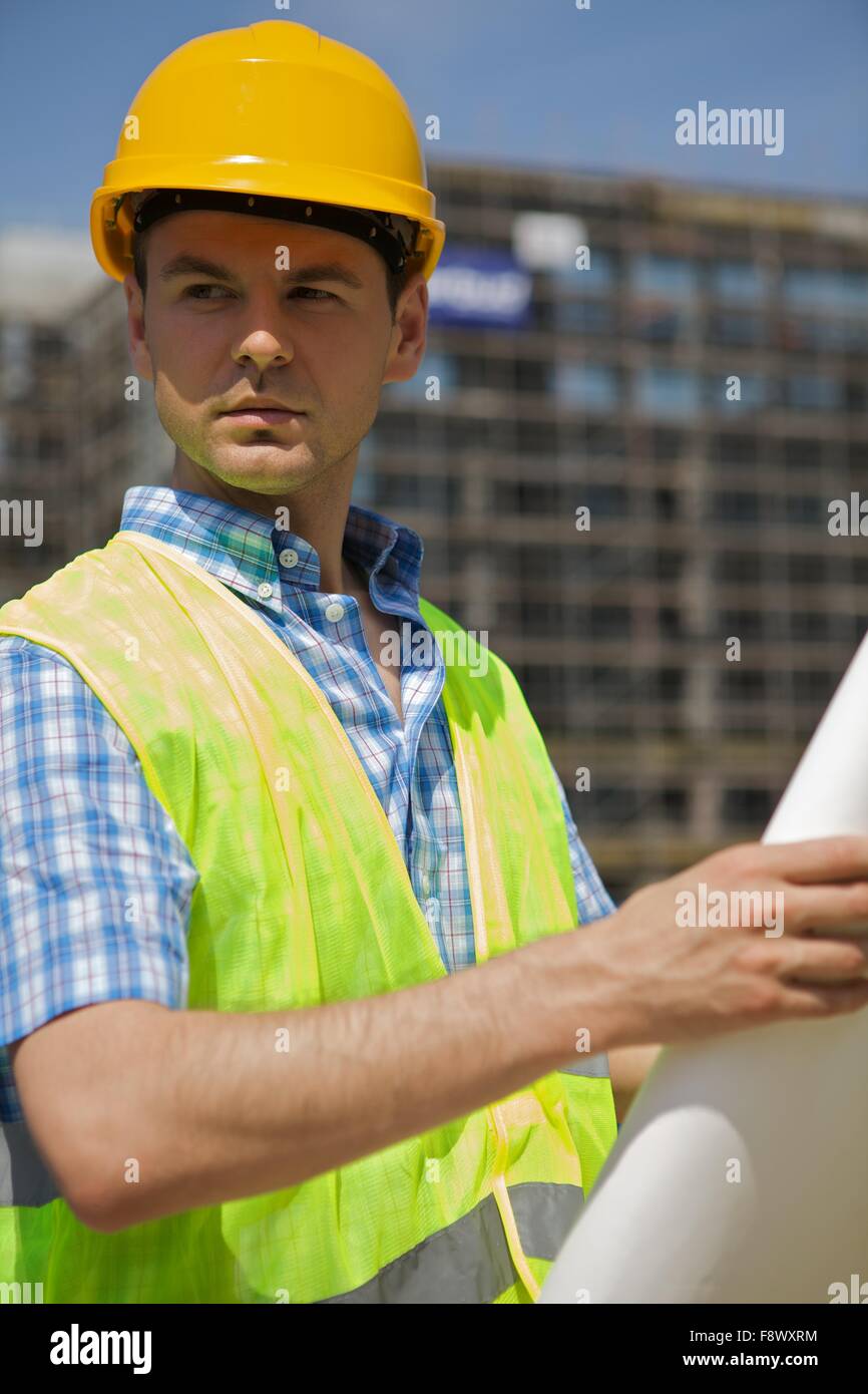 Engineer holding blueprint at construction site Stock Photo - Alamy