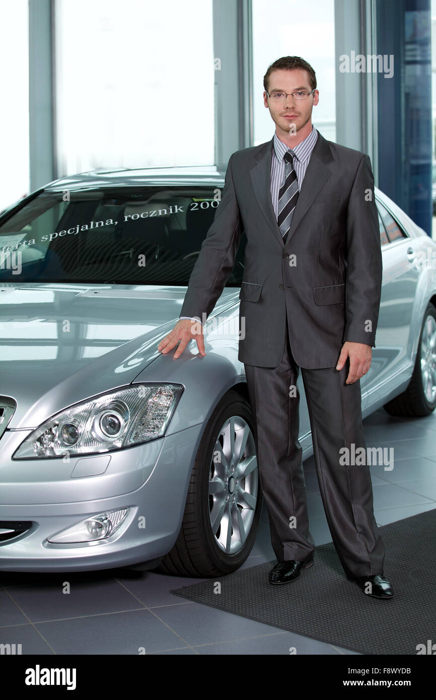Portrait of car salesperson standing in car showroom Stock Photo - Alamy
