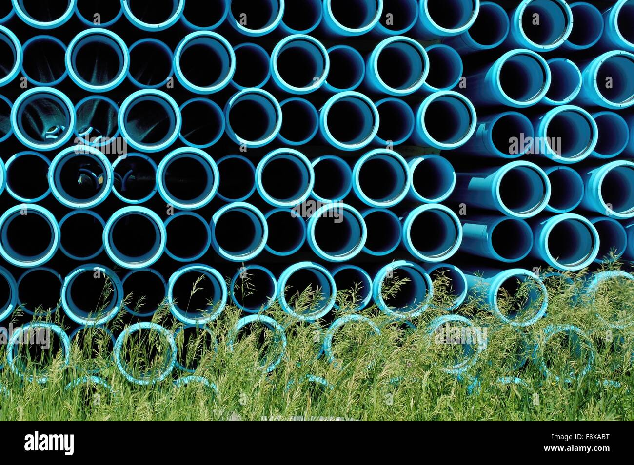 Blue construction pipes staked together in yard Stock Photo - Alamy