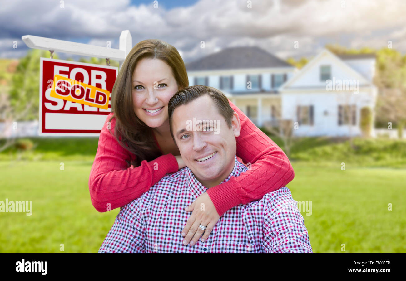 Happy Couple In Front of Sold For Sale Real Estate Sign and Beautiful ...