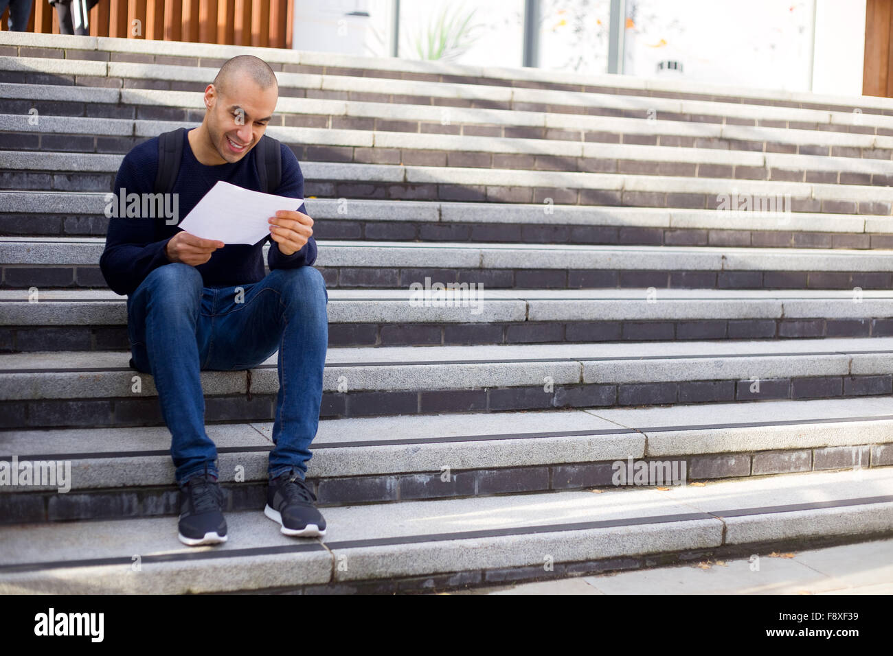 young man sitting on steps reading a letter Stock Photo - Alamy