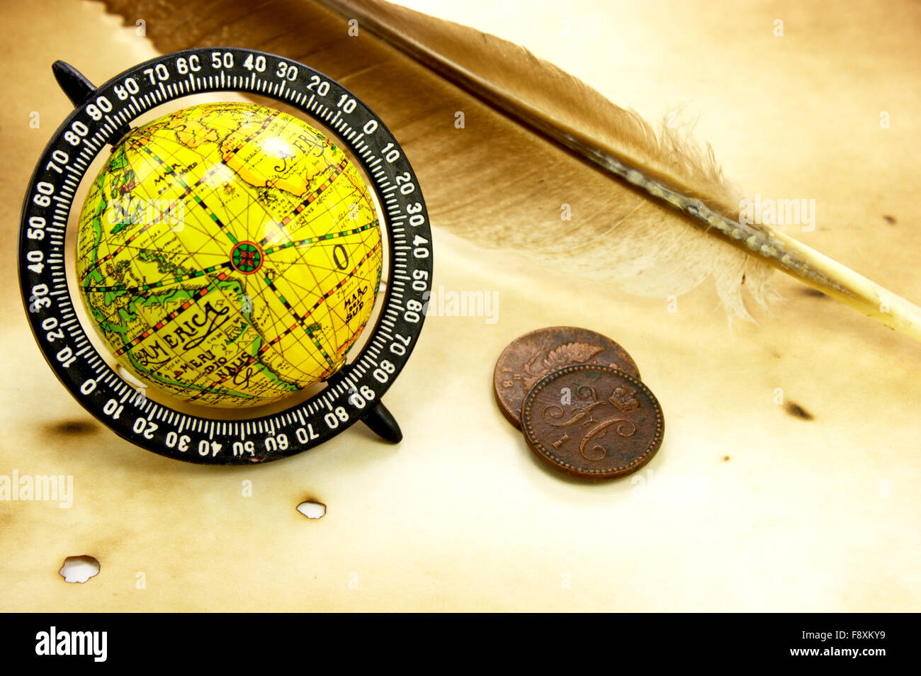 Antique globe, feather and old coins Stock Photo - Alamy
