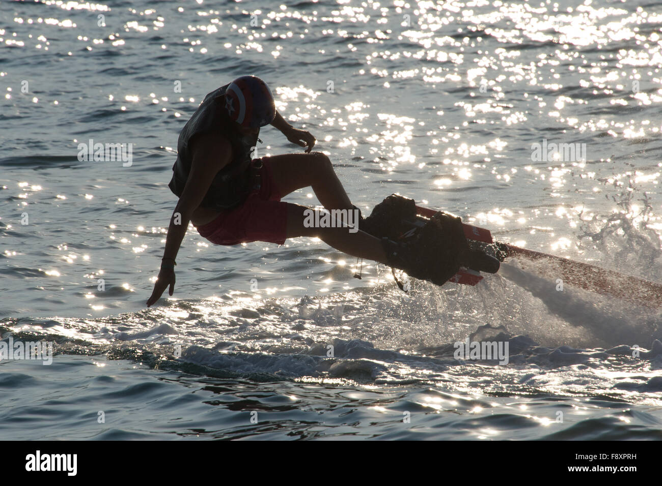 Flyboarder falling over backwards into backlit waves Stock Photo - Alamy