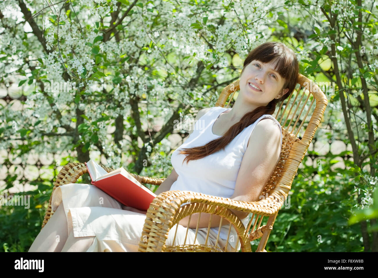 Relaxing girl reading book in bloom garden Stock Photo - Alamy