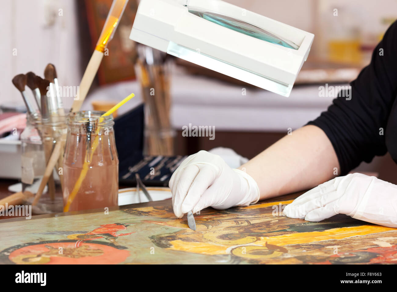 Restorer working on the ancient Christian icon with magnifying at ...