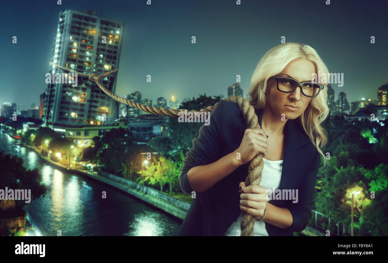 Woman pulling a big building with rope Stock Photo - Alamy