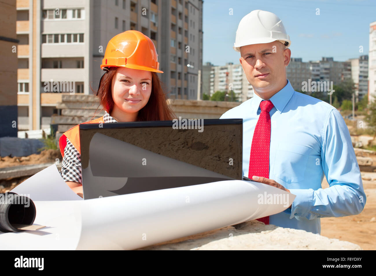 Two architects wearing protective helmet standing in front of building ...