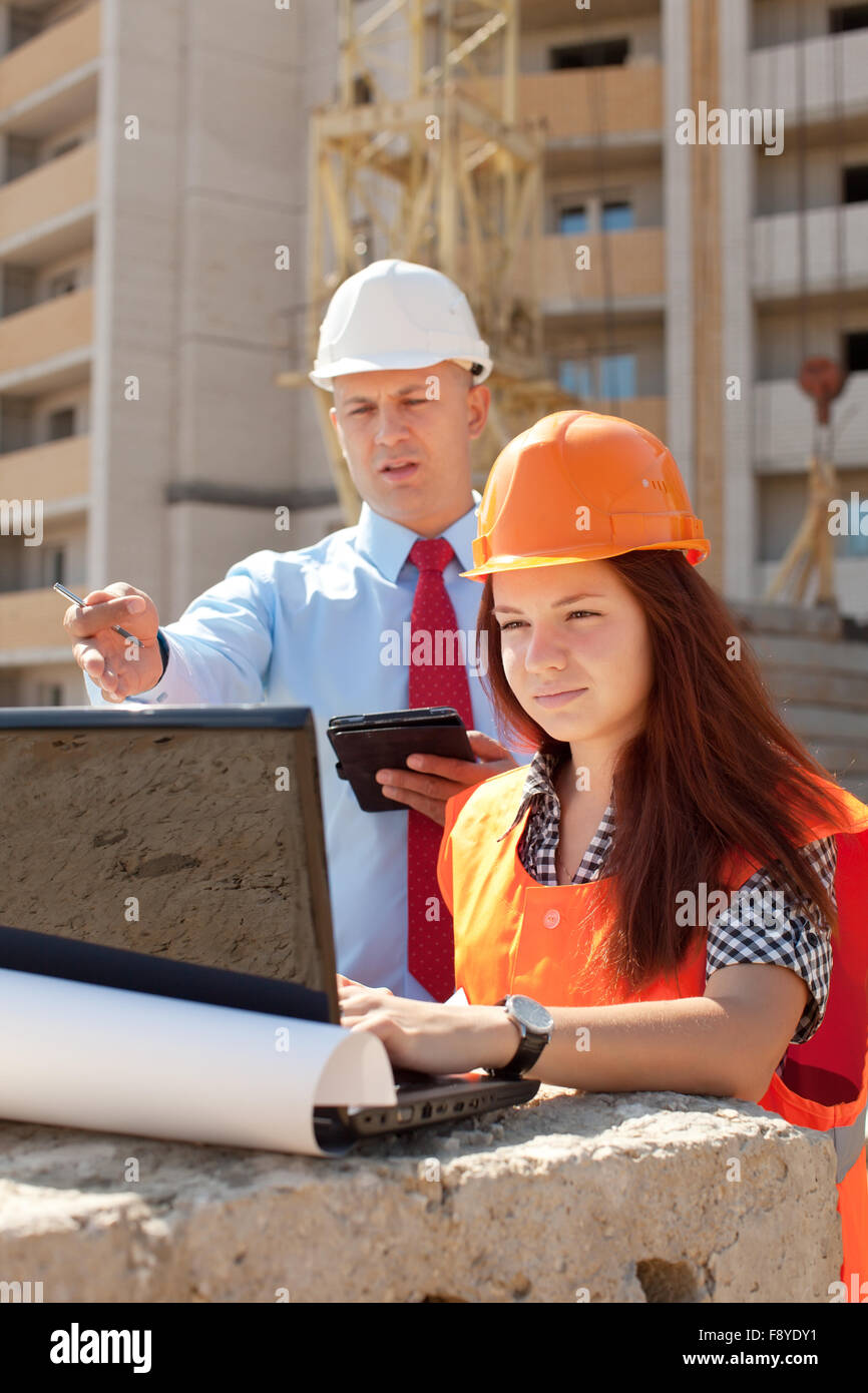 two builders wearing protective helmet works on the building site Stock ...