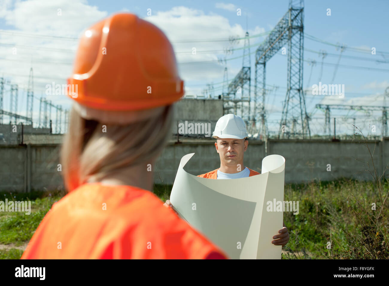 two workers wearing protective helmet works at electrical power station ...