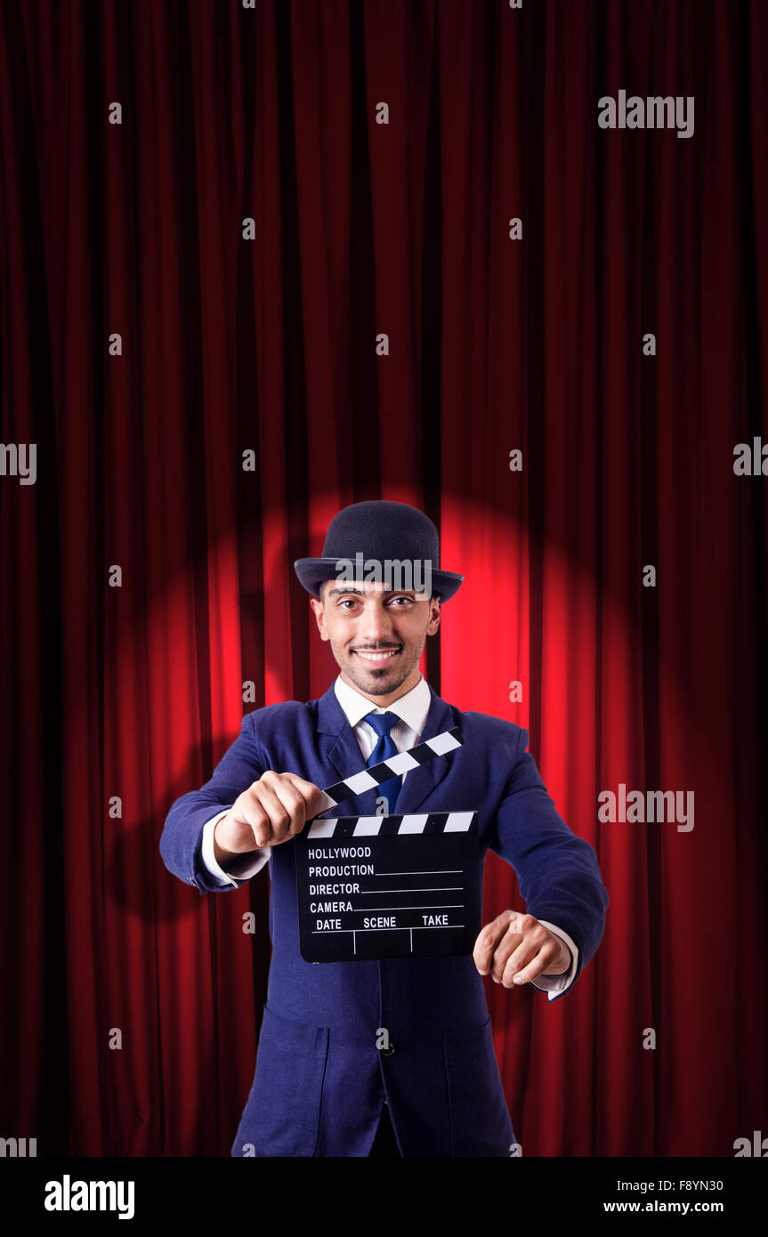 Man with movie clapper on curtain background Stock Photo - Alamy