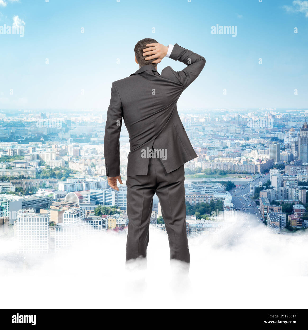 Man standing on clouds in sky looking at city Stock Photo - Alamy