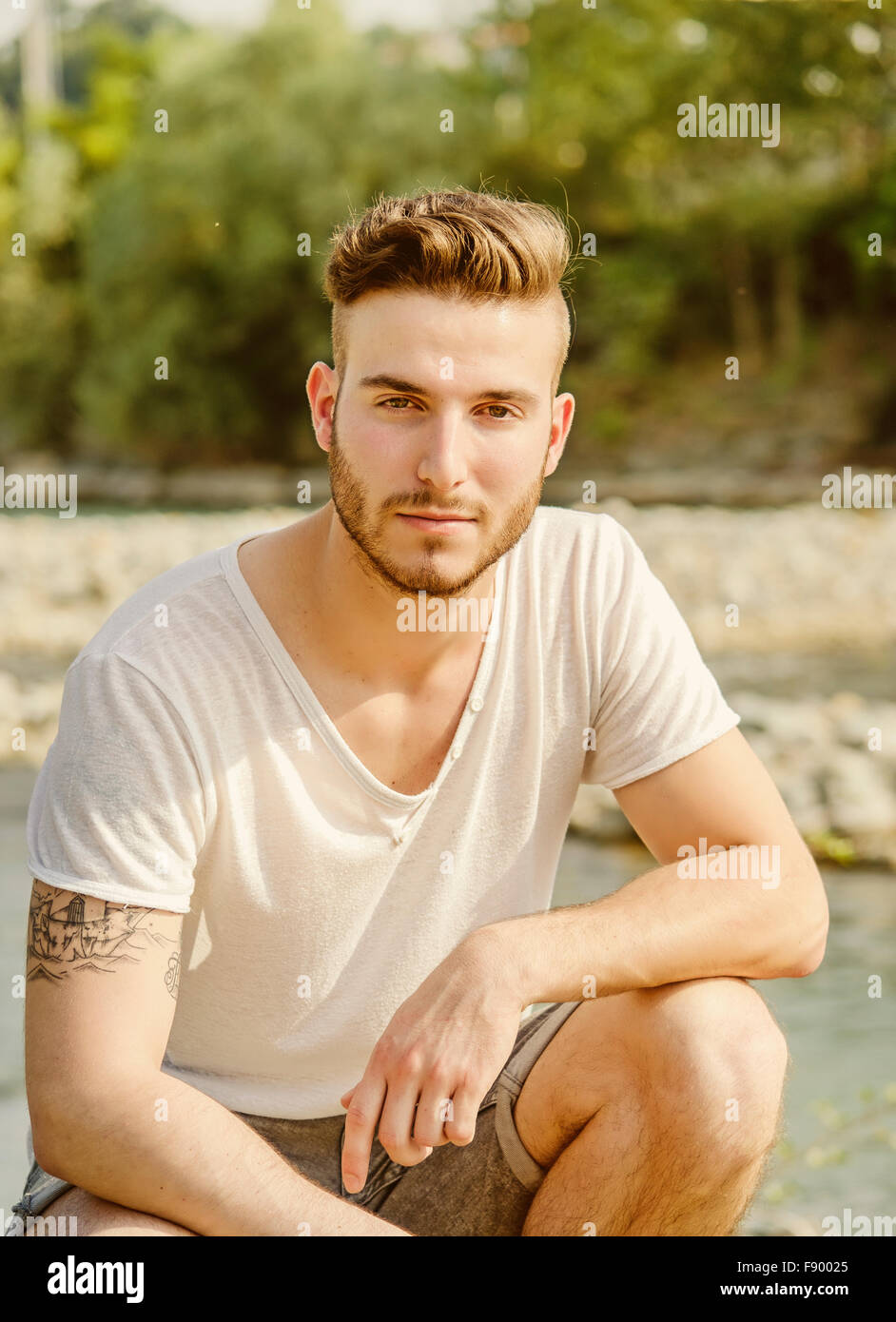 Portrait of handsome young man in white t-shirt outdoors, looking in ...