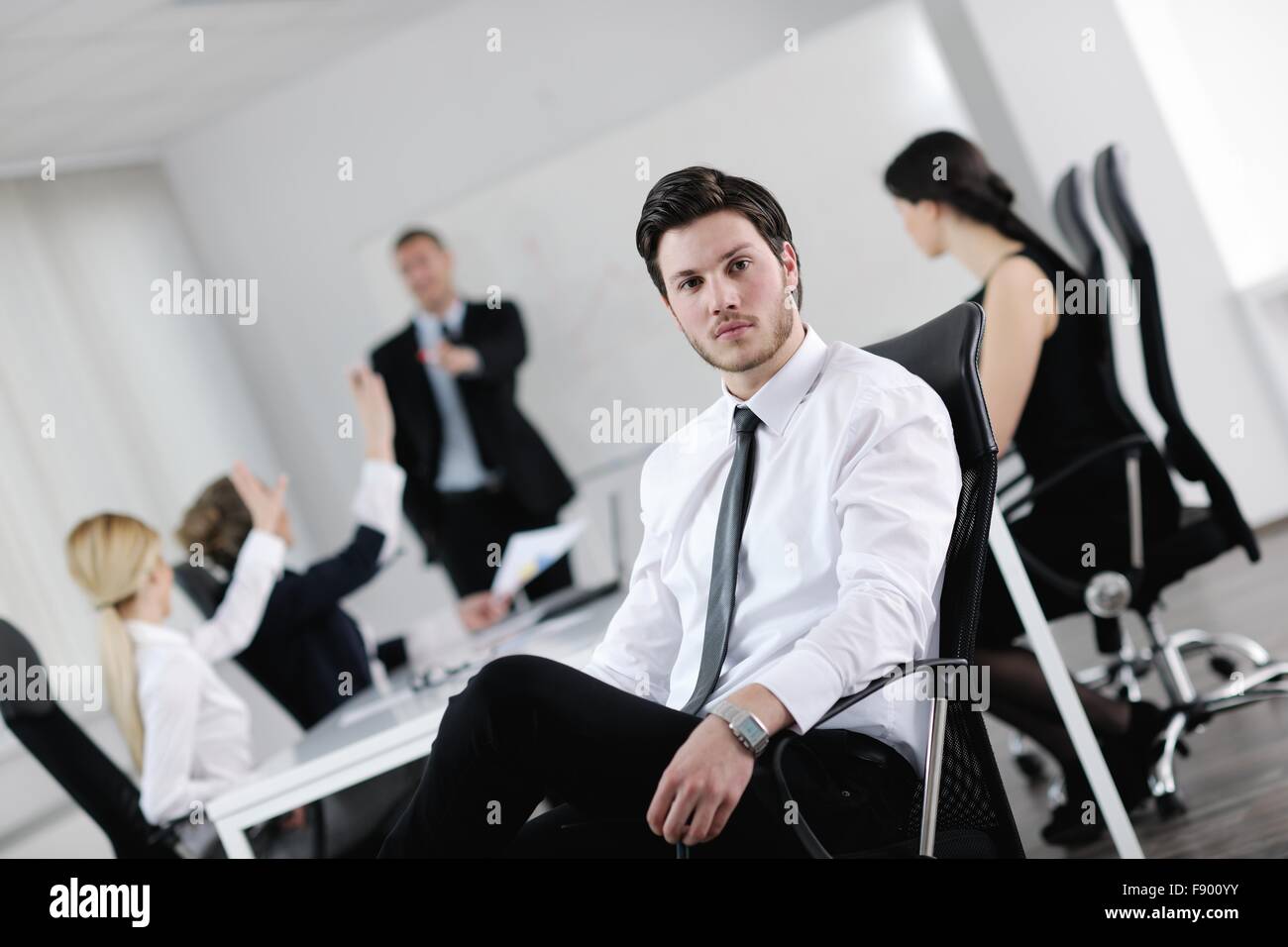Portrait of a handsome young business man with people in background at ...
