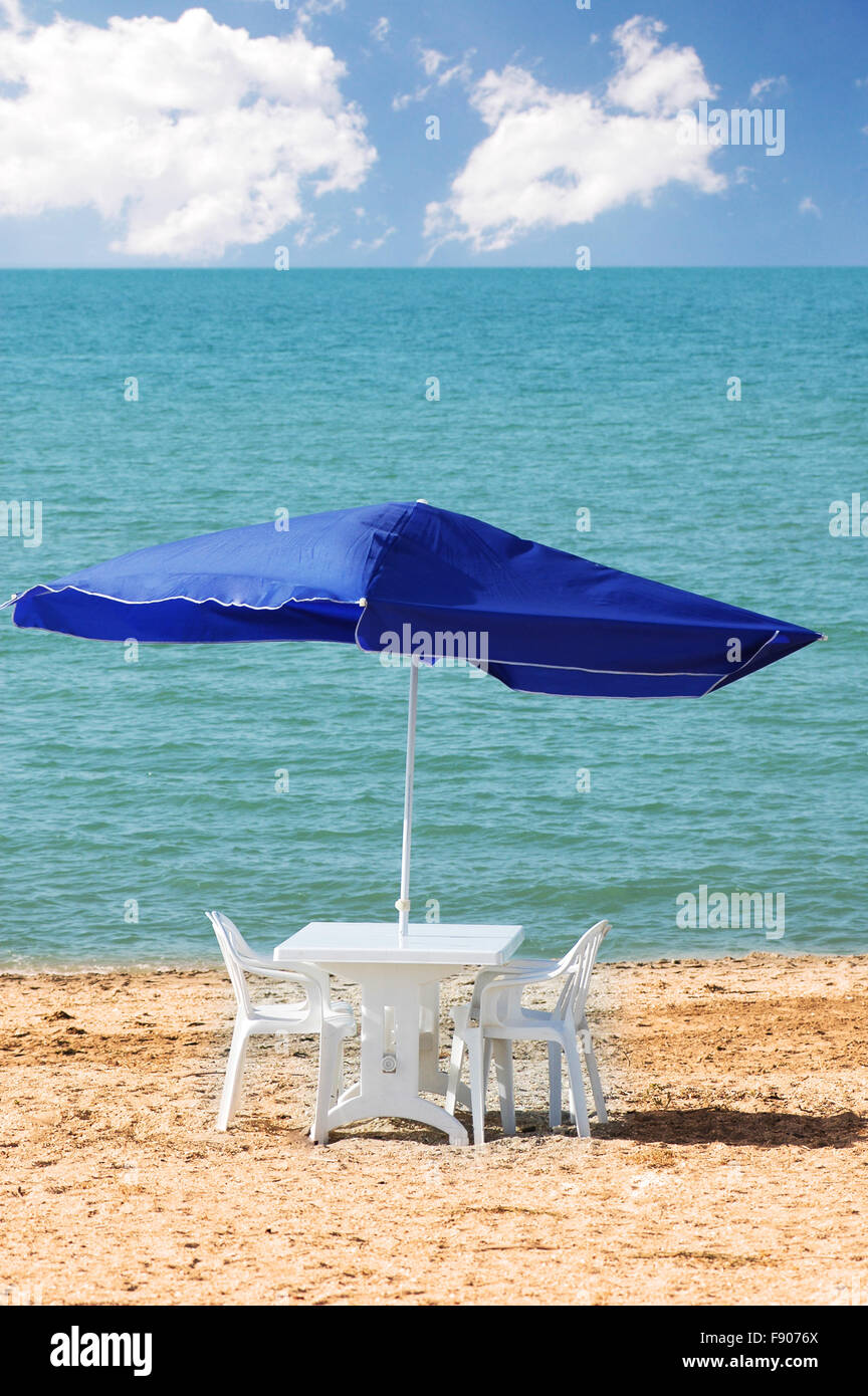 Table, chairs and parasol on the beach Stock Photo - Alamy