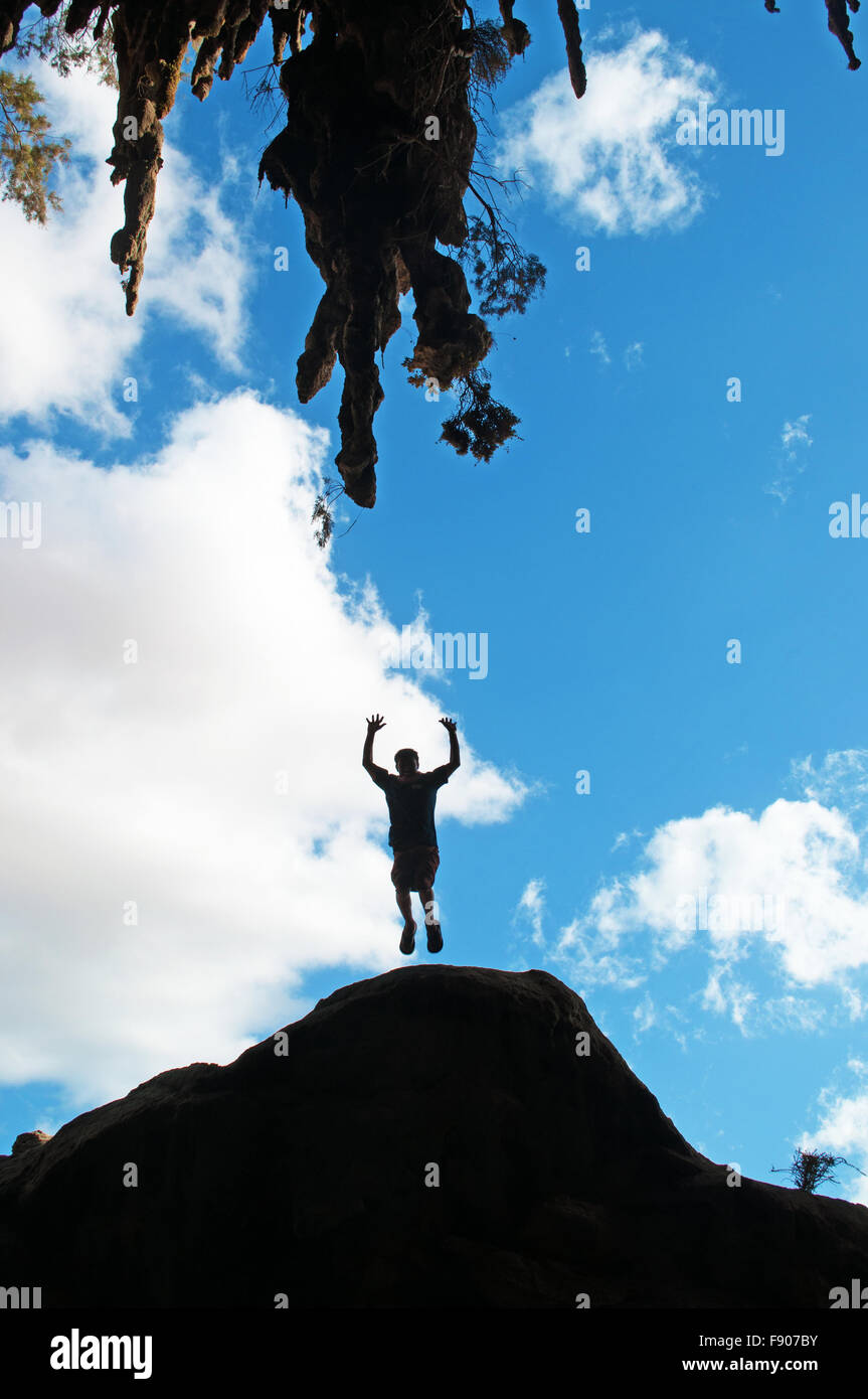 Man jumping backlight in the entrance of the Hoq Cave, Homhil Plateau ...