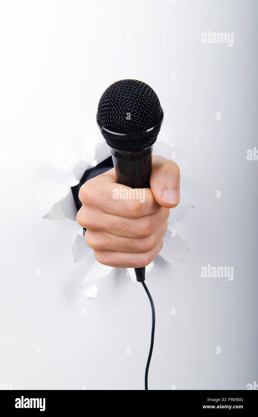 Hand holding microphone through hole in paper Stock Photo - Alamy