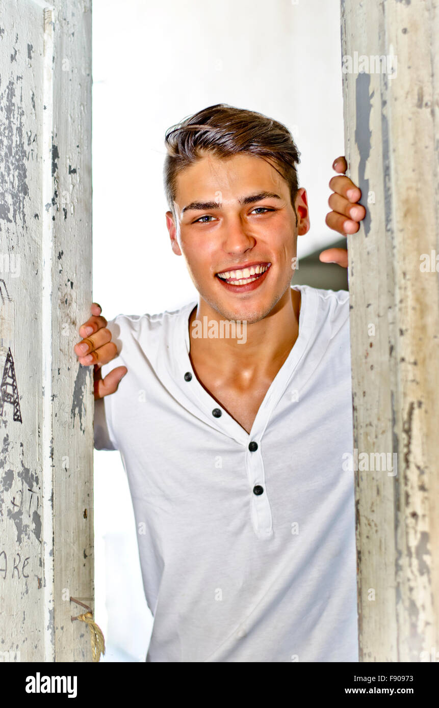 Handsome smiling young man opening old door, inviting viewer to enter ...