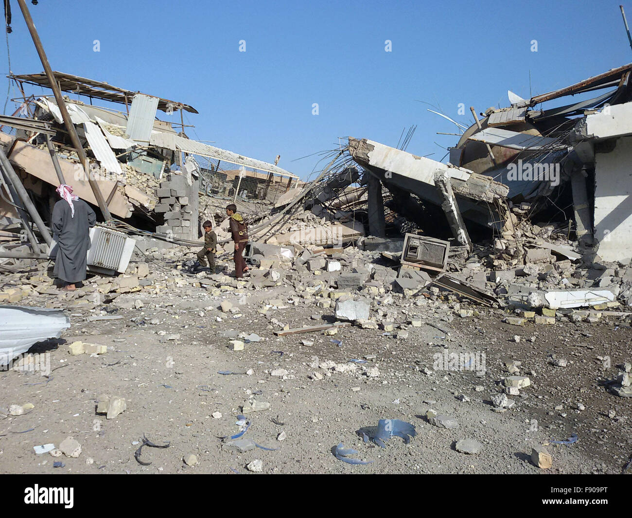Fallujah, Iraq. 12th Dec, 2015. A man and two boys walk past destroyed ...