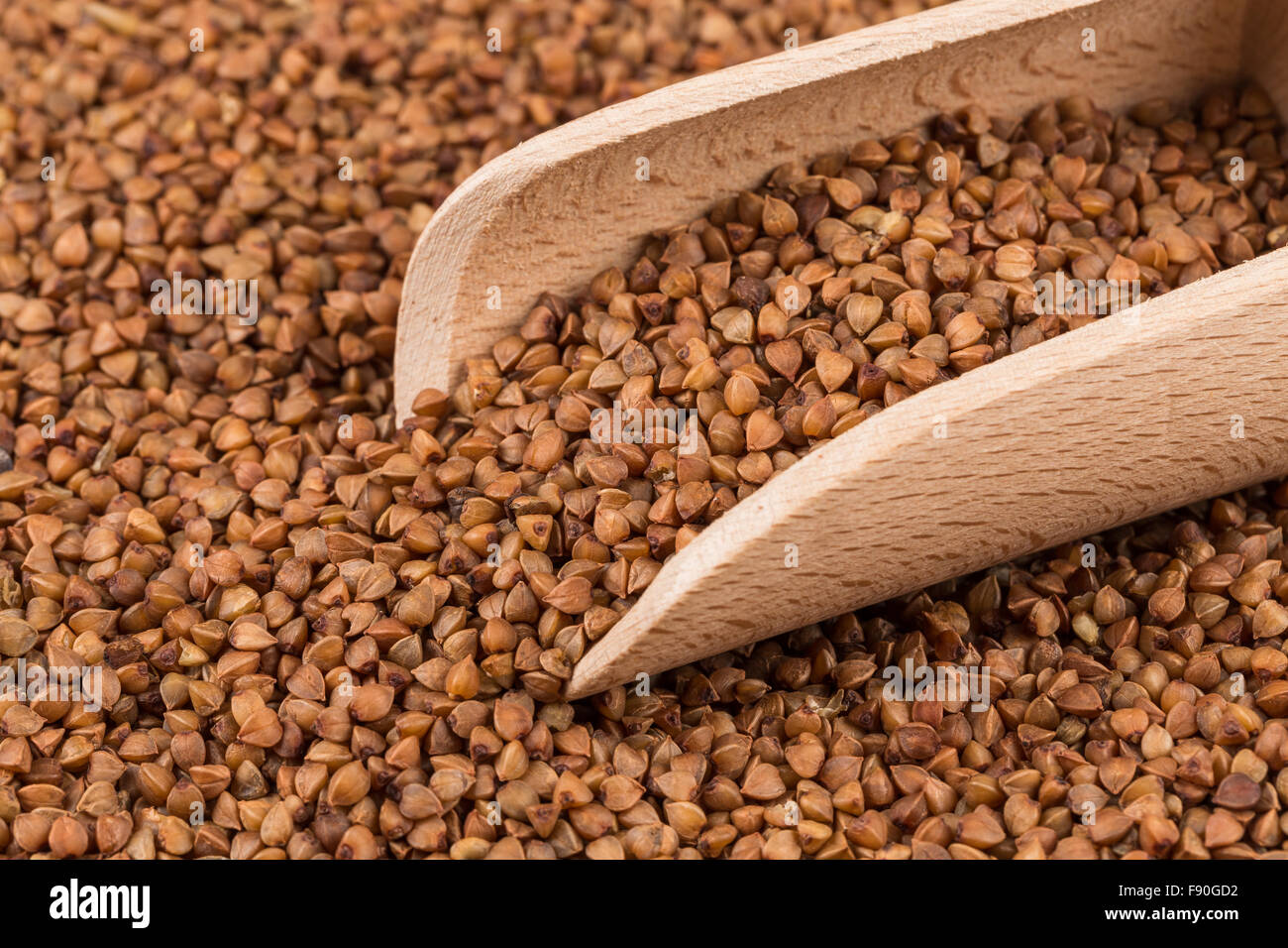 Uncooked buckwheat on wooden spoon. premium buckwheat groats on white ...