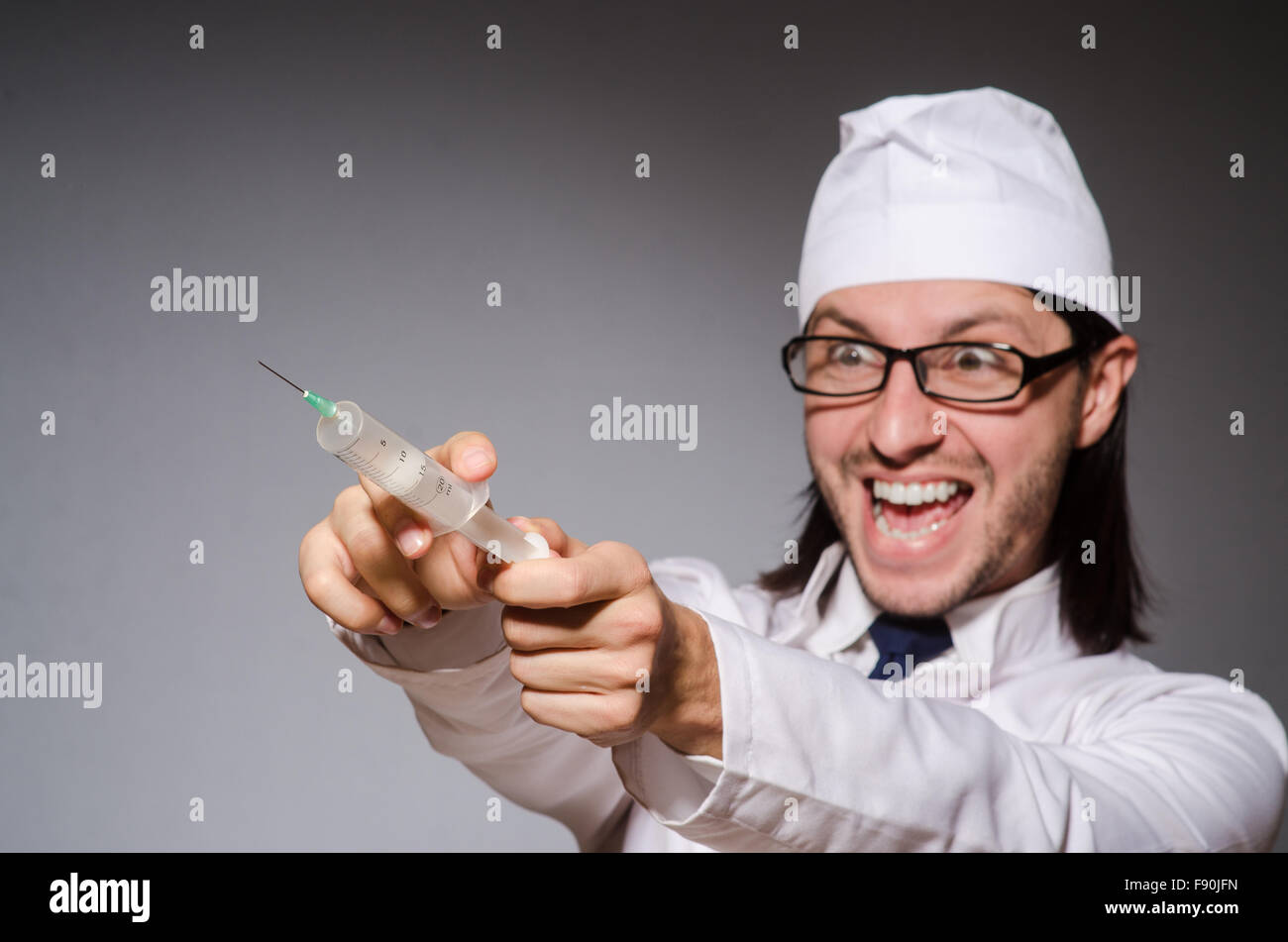 Young doctor man with syringe against grey background Stock Photo - Alamy