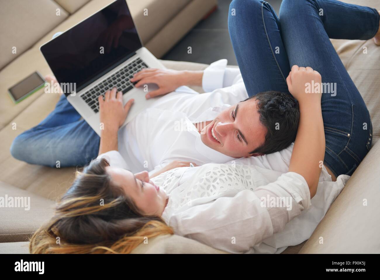 happy young relaxed couple working and playing on laptop computer at ...