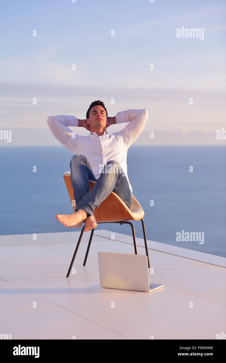 handsome young man relaxing and working on laptop computer at home ...