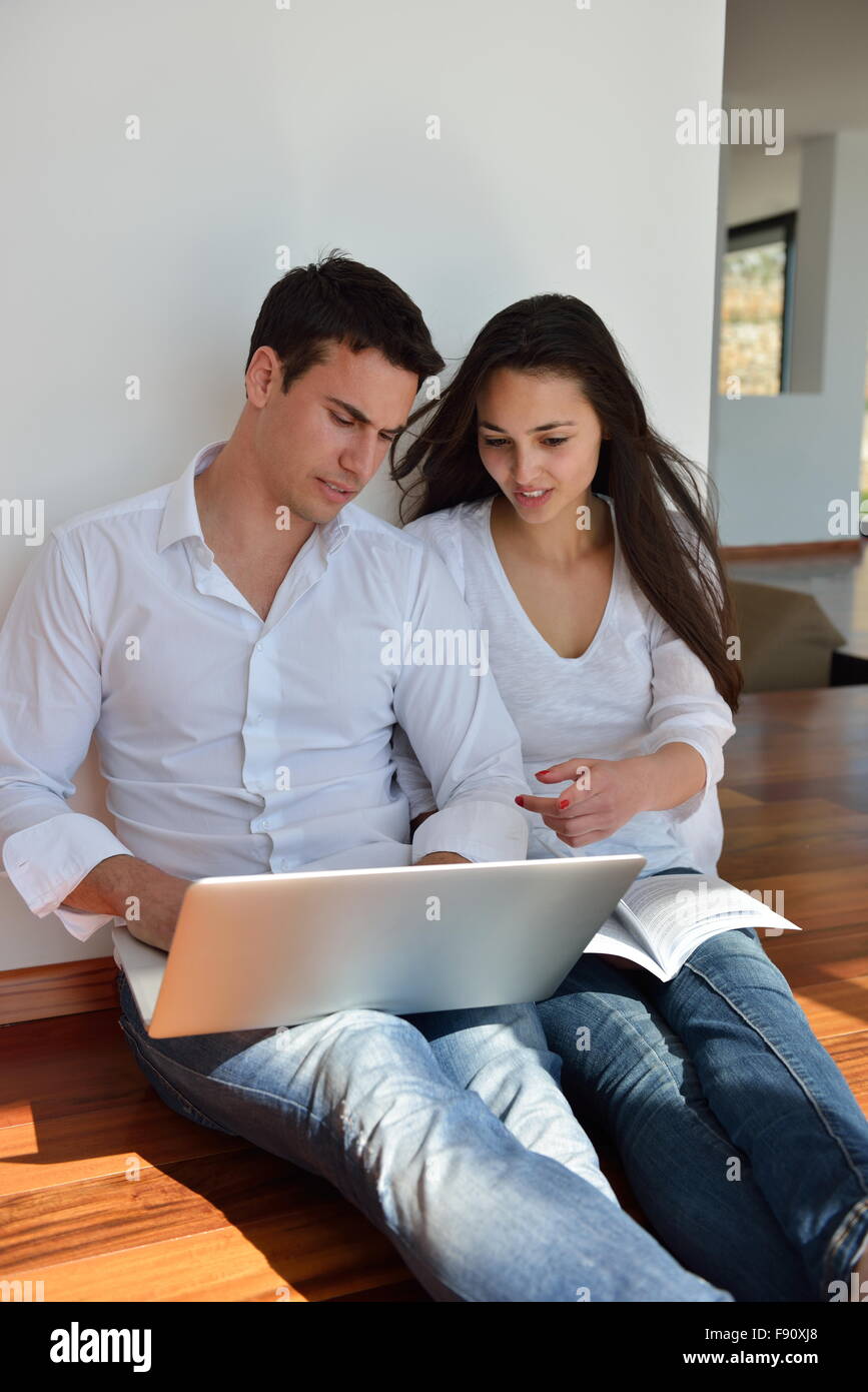 happy young relaxed couple working on laptop computer at modern home ...