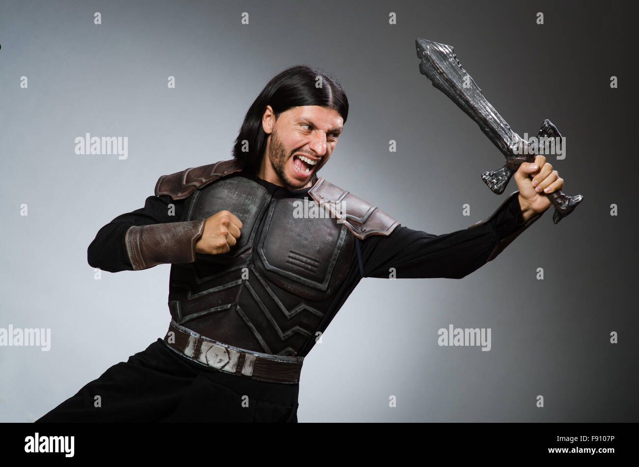 Angry knight with sword against dark background Stock Photo - Alamy