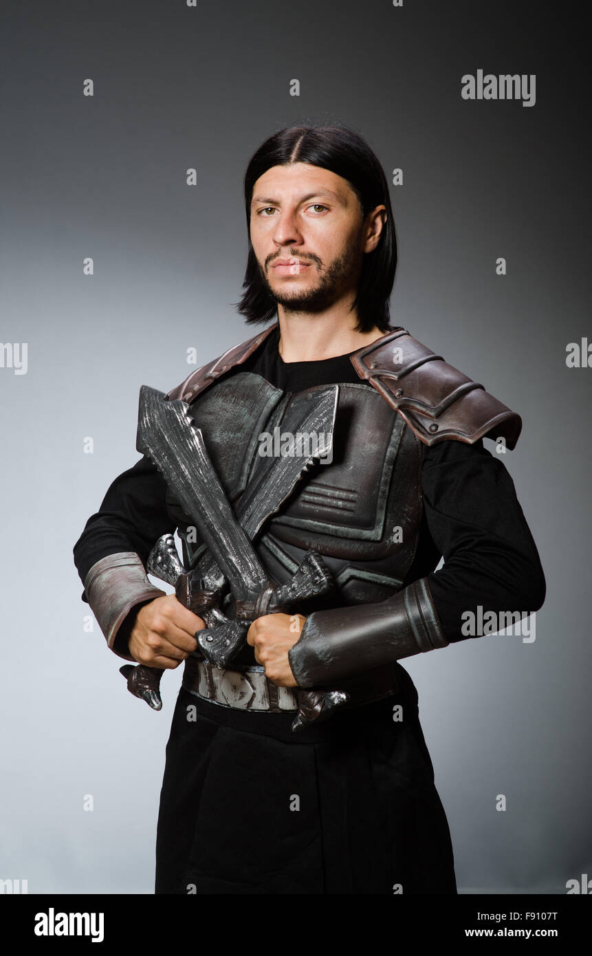 Angry knight with sword against dark background Stock Photo - Alamy