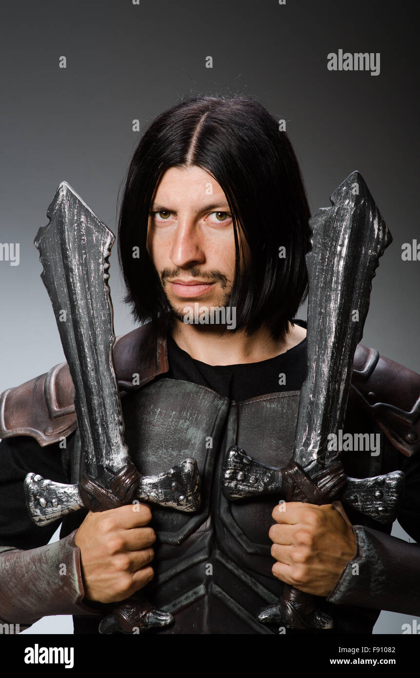 Angry knight with sword against dark background Stock Photo - Alamy