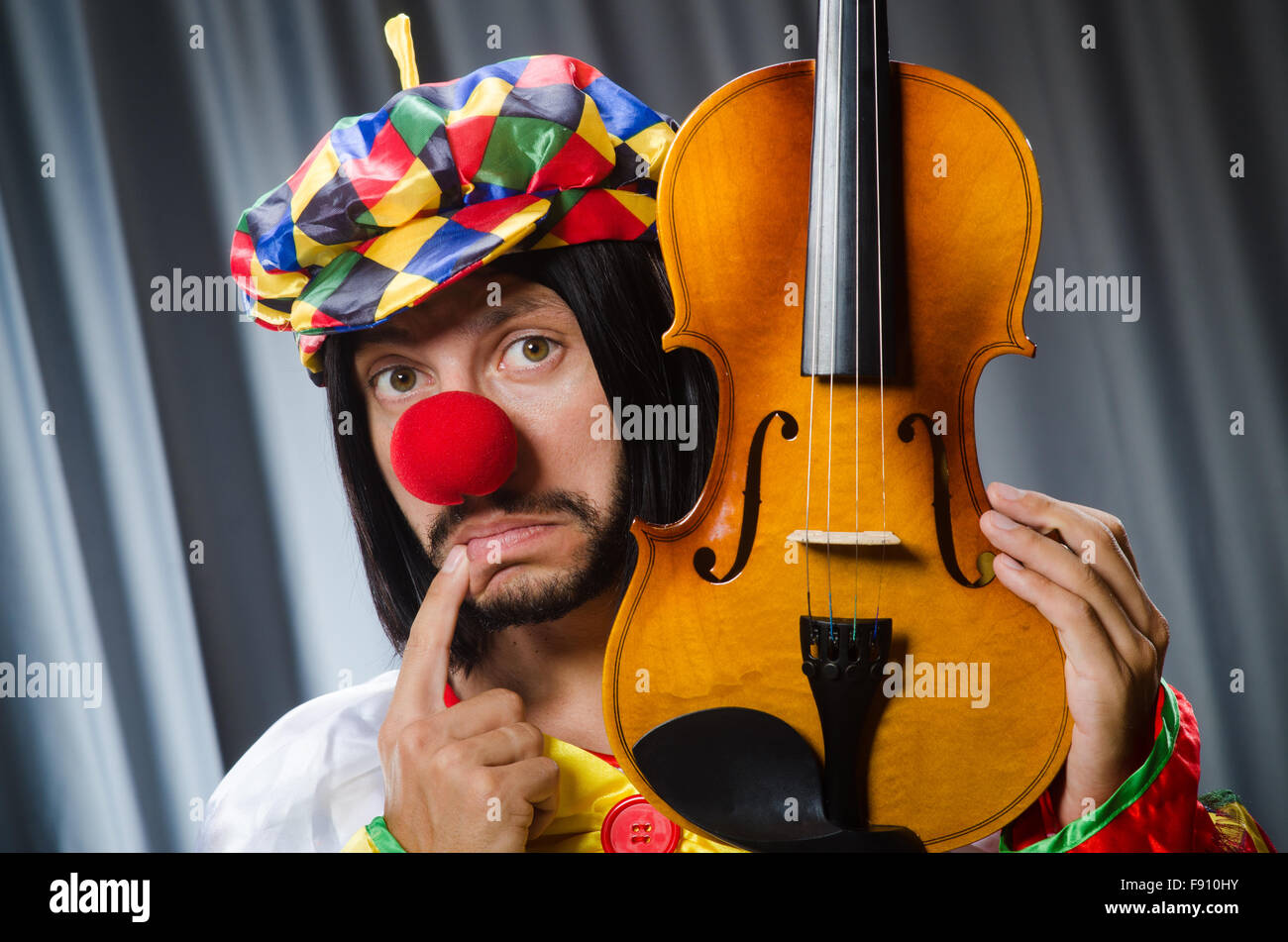 Funny clown plyaing violin against curtain Stock Photo - Alamy