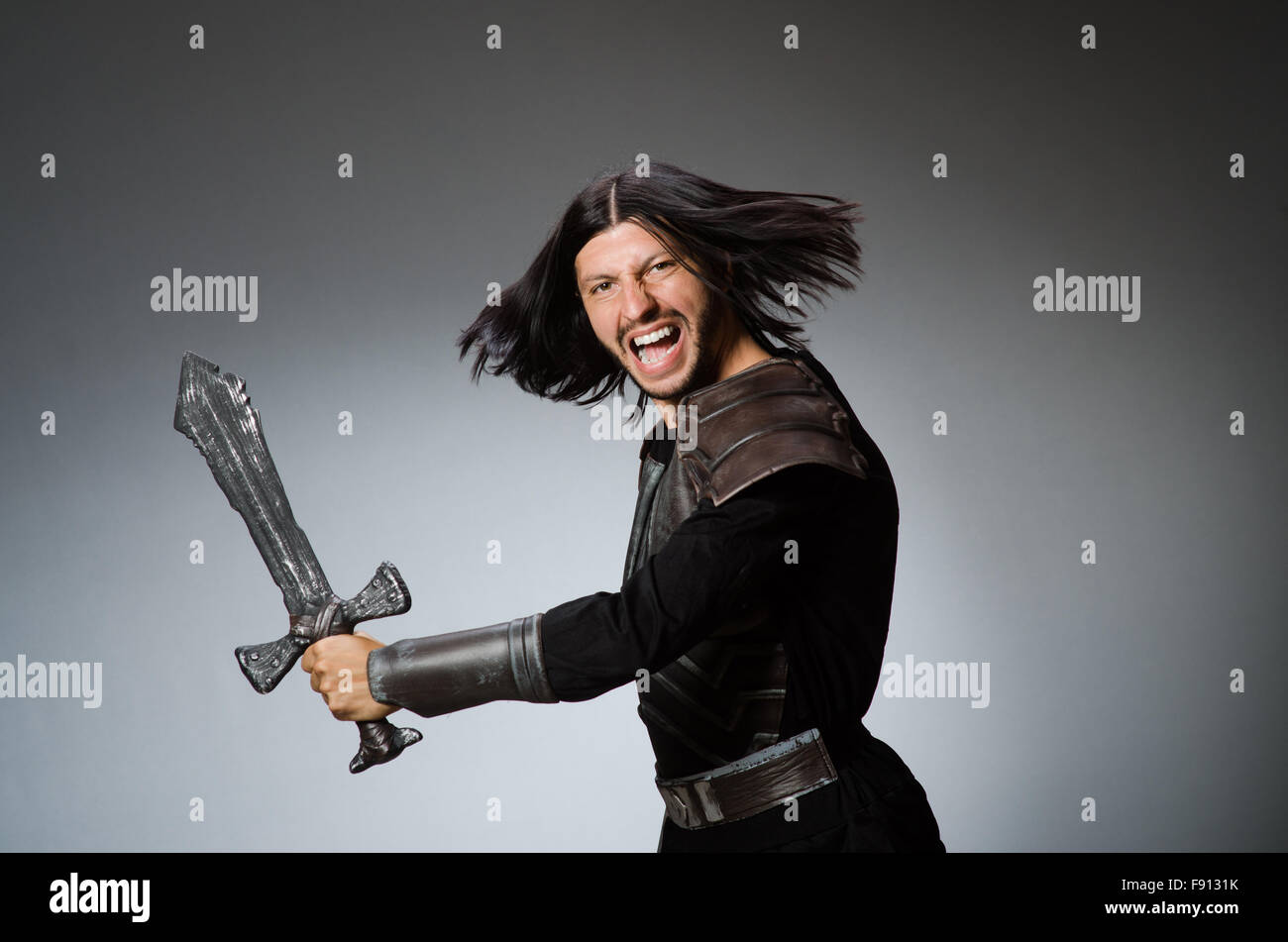 Angry knight with sword against dark background Stock Photo - Alamy