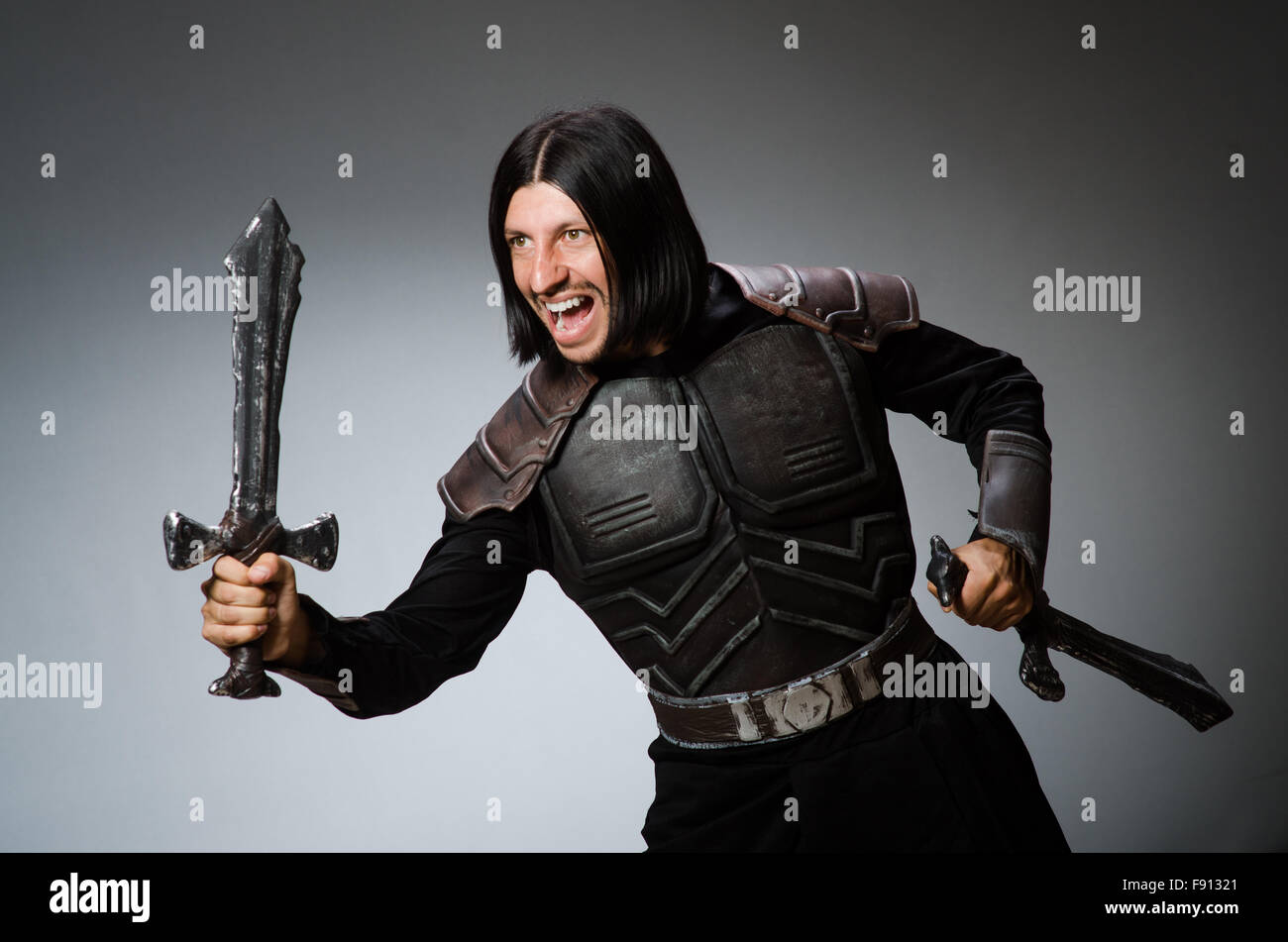 Angry knight with sword against dark background Stock Photo - Alamy