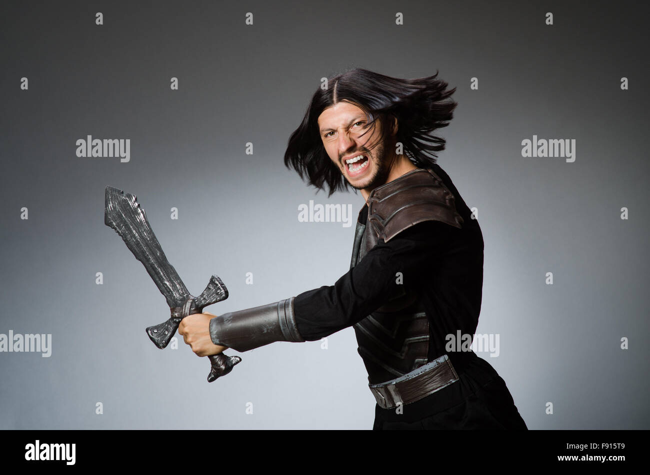 Angry knight with sword against dark background Stock Photo - Alamy