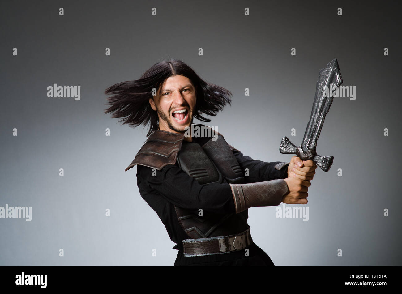 Angry knight with sword against dark background Stock Photo - Alamy
