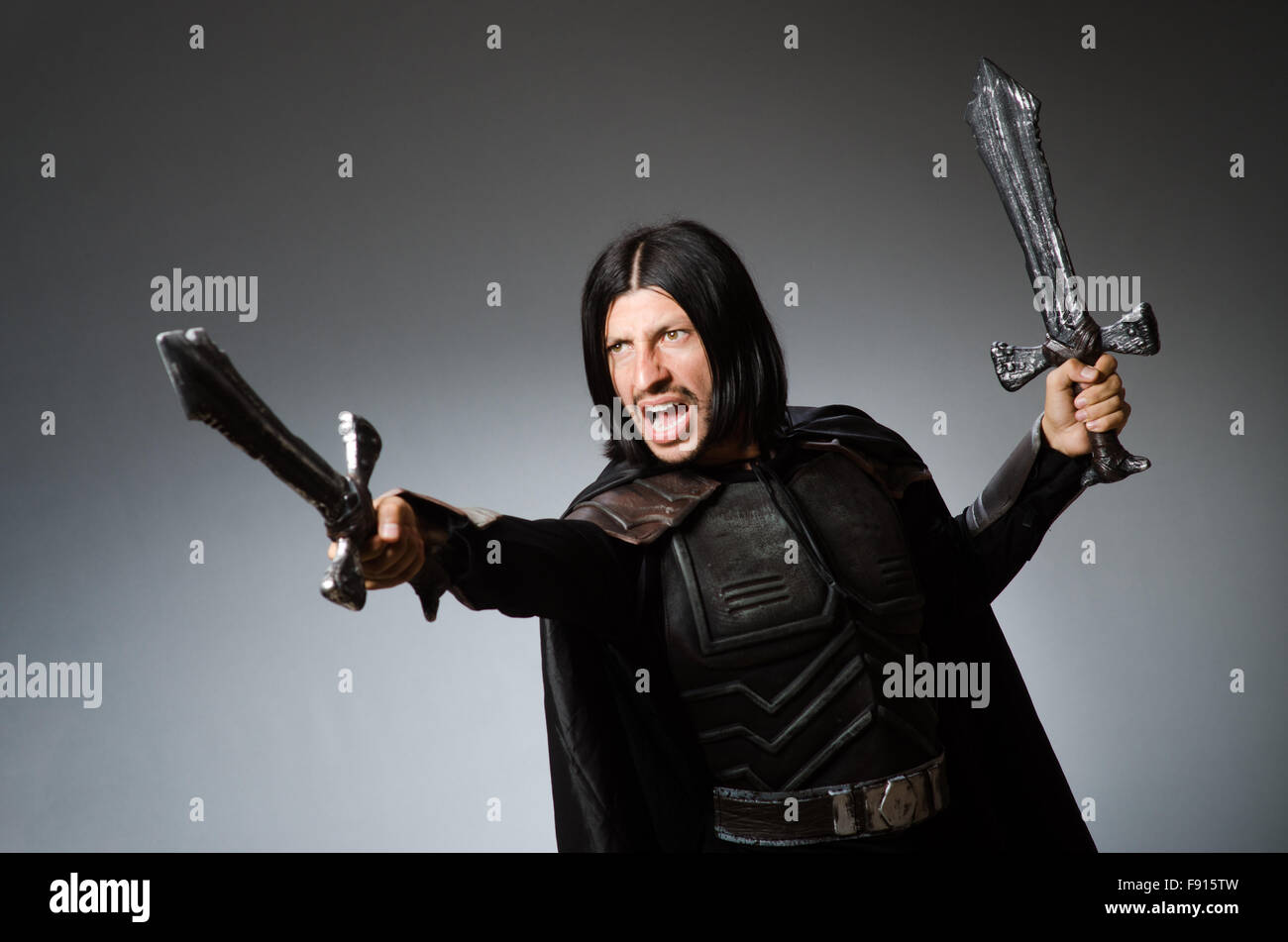 Angry knight with sword against dark background Stock Photo - Alamy
