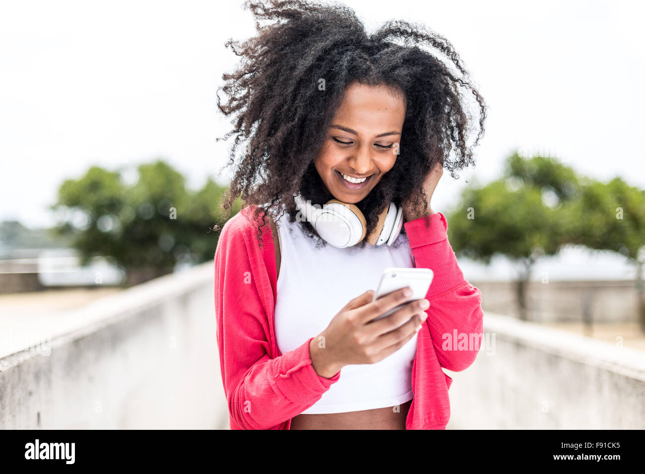 A young mixed-race woman listening to music on a smartphone with ...