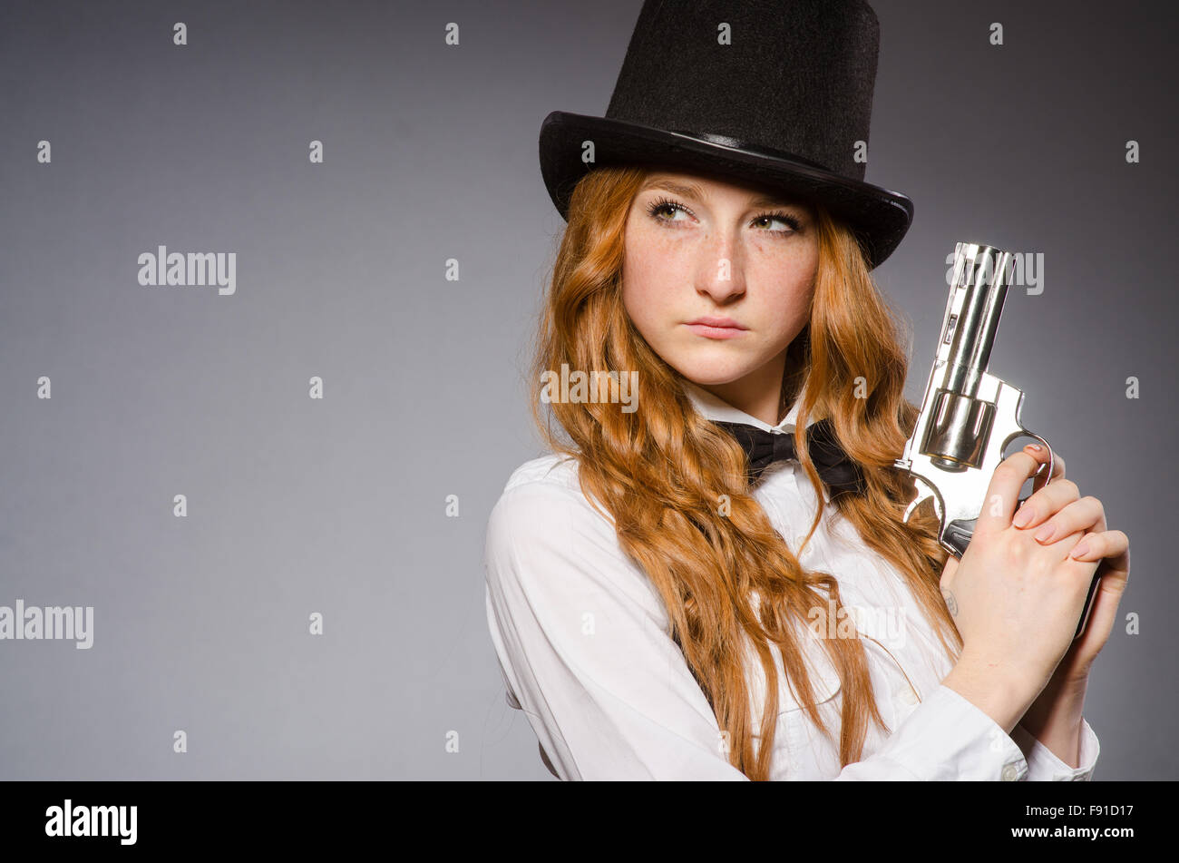 Pretty girl wearing retro hat and holding weapon isolated on gray Stock ...
